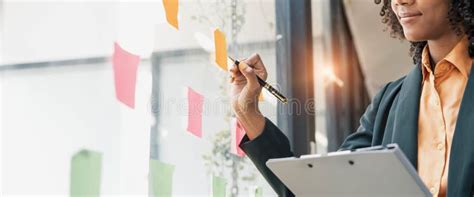 Attractive Concentrated Business Lady In Creating To Do List Using Multi Coloured Post It Sticky