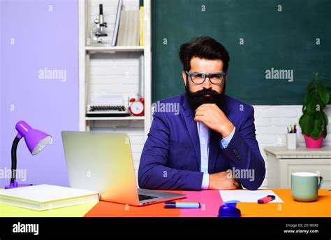 Serious University Teacher Sitting At Desk Working With Laptop In Classroom Teacher Job Male