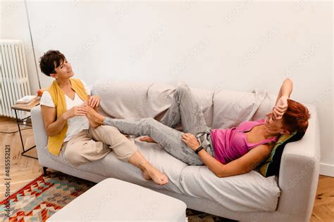 Mature Woman Doing Her Girlfriends Foot Massage While Resting On Sofa