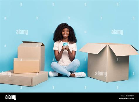 Full Body Photo Of Cheerful Pretty Person Sit Floor Hands Hold Telephone Carton Parcels Isolated
