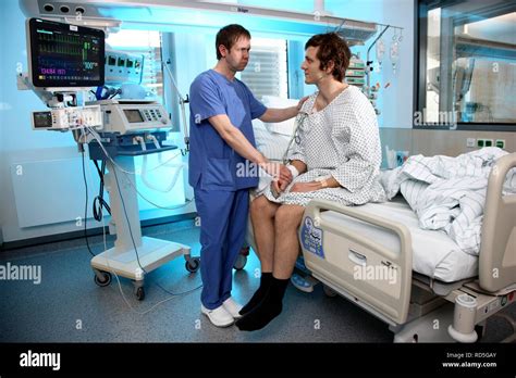 Male Intensive Care Nurse Mobilising A Patient First Physical