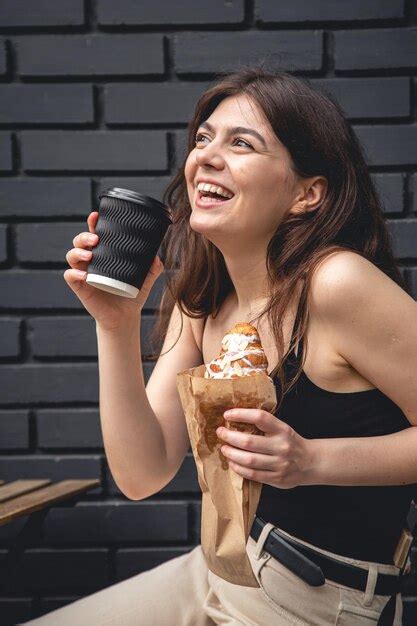Une Jeune Femme Avec Un Croissant Et Une Tasse De Café Contre Un Mur De