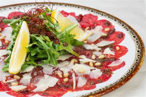 Beef Carpaccio Cold Appetizer With Parmesan Capers And Arugula On White