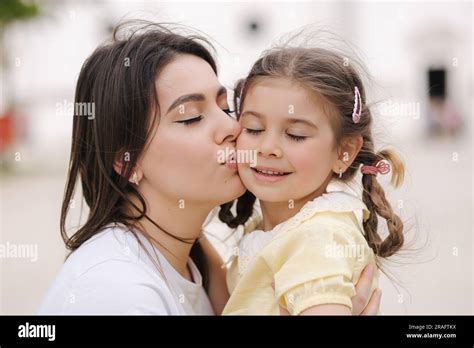 Close Up Portrait Of Adorable Daughter With Beautiful Mom Woman Kiss Her Daughter Stock Photo