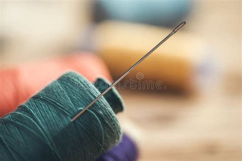 Needle With Threaded Yellow Thread Passing The Thread Through A Black