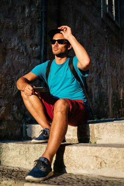Handsome Guy Sitting In The Sun With His Phone Del Colaborador De