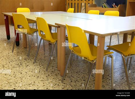 Small Yellow Chairs And Low Tables Inside A School Classroom Of The