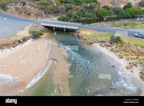 Aerial View Of A Wave Rolling Up A Coastal River Mouth And Under A