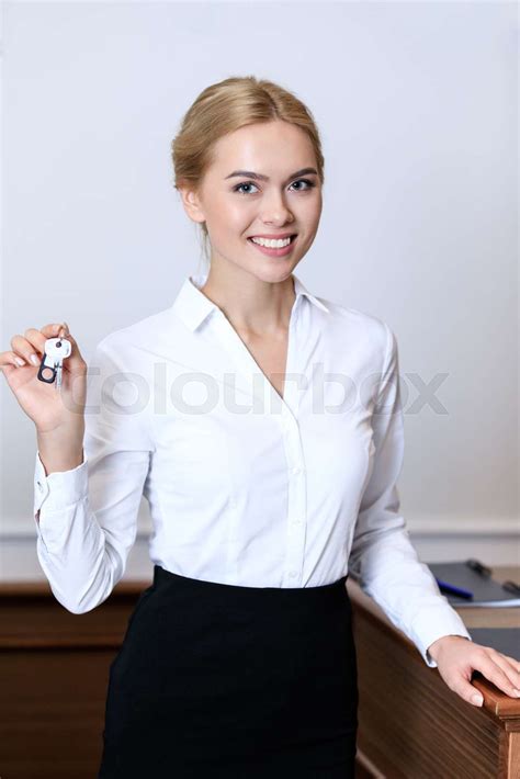 Smiling Attractive Receptionist Holding Key At Reception Desk Stock Image Colourbox