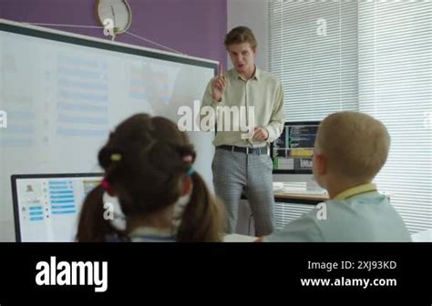 Back View Of Girl Putting Her Hand Up When Giving Answer To Male Teacher During Programming