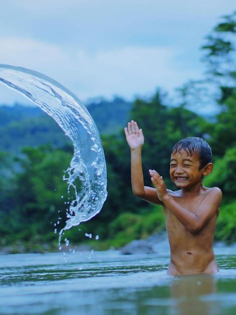 Shirtless Boy Playing In River Premium Photo