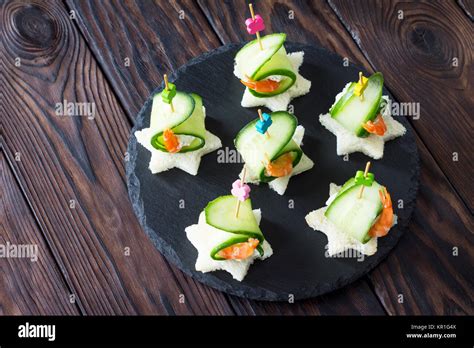 Appetizer Canape With White Bread Cucumber Ricotta And King Prawns On A Wooden Table Stock
