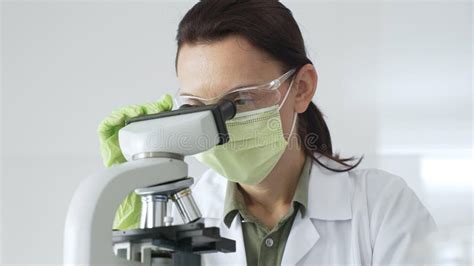 Female Scientist Examining Specimen Placing Slide Under Microscope