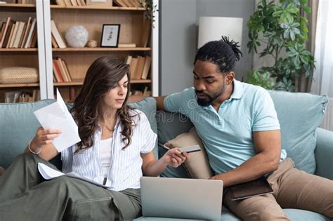 Young Couple Man And Woman Roommates Sitting At Home On Sofa Having