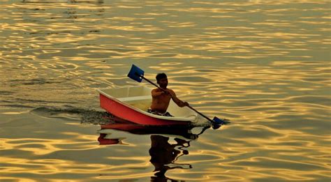 Premium Photo Shirtless Mature Man Rowing Rowboat In Lake At Sunset