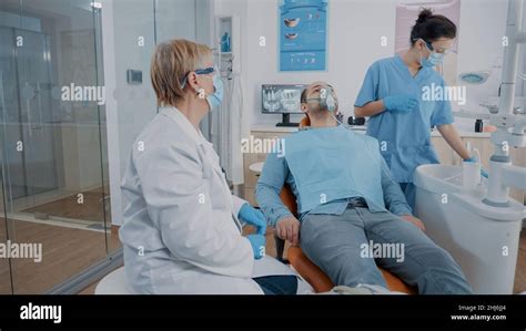 Dentistry Assistant Putting Oxygen Mask On Face Of Patient To Do