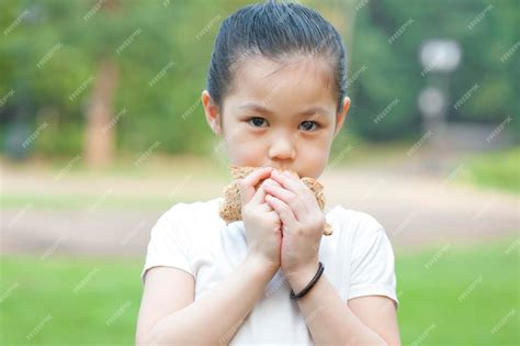 Premium Photo Close Up Portrait Of Cute Girl Eating Bread While Standing Park