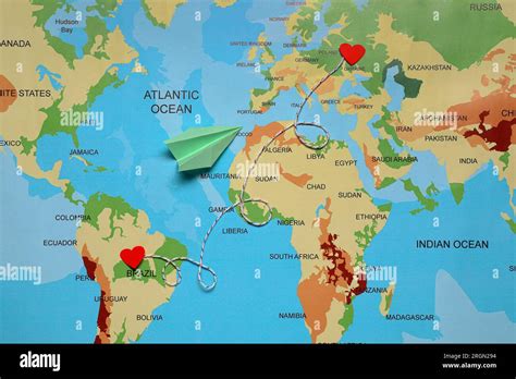 Paper Plane And Decorative Cord Between Two Red Hearts On World Map