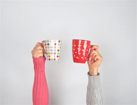 Premium Photo Cropped Hands Holding Mugs Against White Background