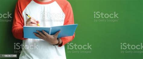 고등학교 종이 노트북에 캐주얼 쓰기대학생 학교 캠퍼스에서 복사 공간이있는 녹색 벽의 요새에 서있는 십대 학생 쓰기 노트북 대학 교육 카피 공간에 대한 스톡 사진 및 기타