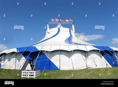 Blue And White Big Top Circus Tent In Field With Flags From Around