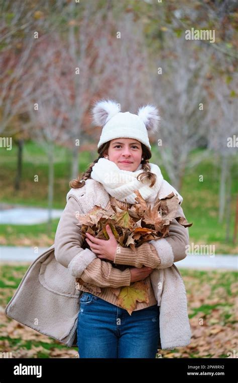 Preteen Girl Grabbing A Bunch Of Brown Leaves During Autumn Season