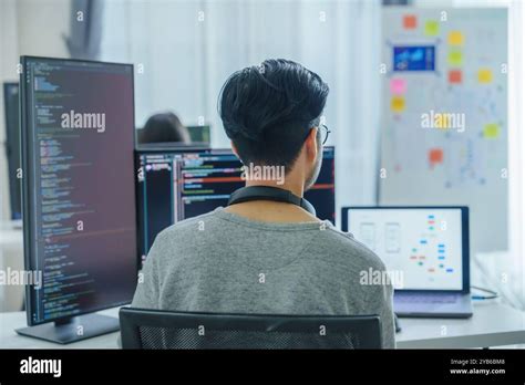 Asian Software Developers Working On Multiple Screens Displaying Code