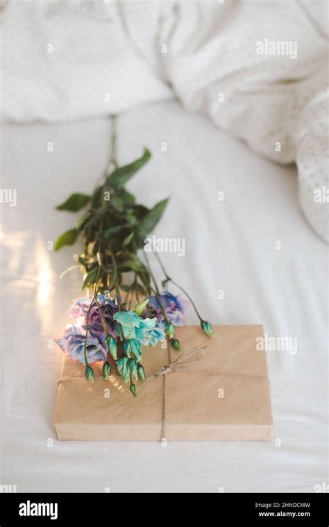 Bouquet Of Flowers And A T Covered In Paper On Crumpled White Bed