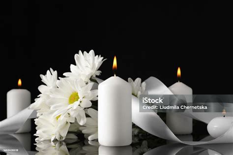 White Chrysanthemum Flowers And Burning Candles On Black Mirror Surface