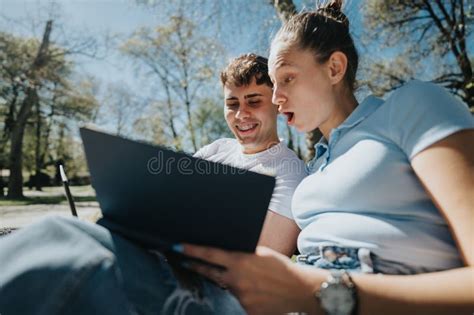 Students Sharing Ideas While Studying Together In A Sunny Park Stock