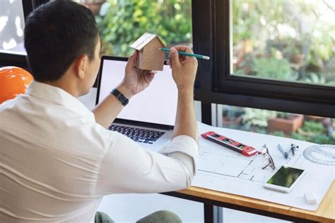 Premium Photo Rear View Of Mid Adult Architect Writing On House Model While Sitting At Office