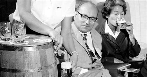 Flight Attendant For The German Airline Lufthansa Serving Draft Beer From A Wooden Barrel And