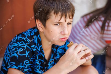 Preadolescent Boy Sitting On Stone Steps With His Sister And Eating Ice