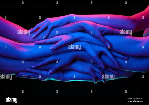 Overlapping Hands In Multicolored Neon Lighting Against Black Studio