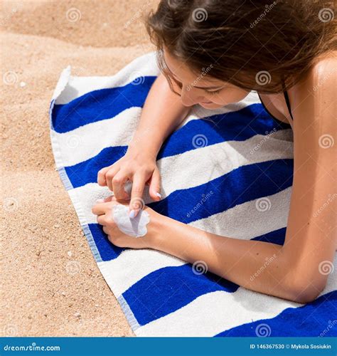 Cute Woman Is Applying Sunscreen On Her Hand With The Finger Sunbathing
