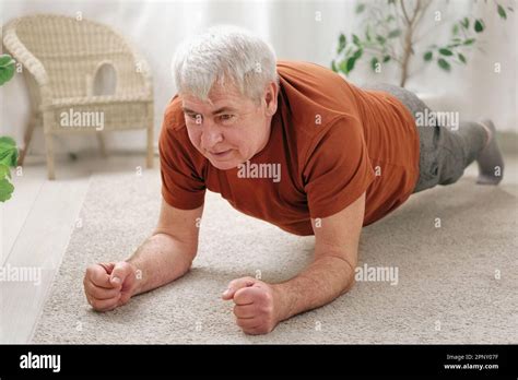 Happy Smiling Mature Senior Man Doing Exercises Of Gymnastics At Home