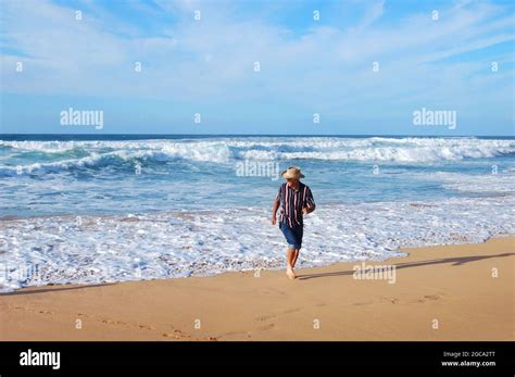 Male Tourist Barefoot And Rolled Up Jeans Runs From Breaking Waves On