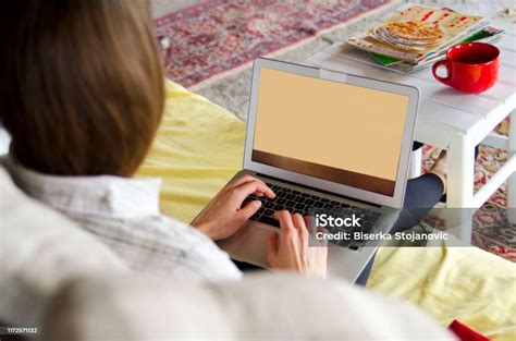 소파에 앉아 노트북 컴퓨터에 입력 하는 여자의 후면 보기 노란색 바탕 화면 20 29세에 대한 스톡 사진 및 기타 이미지