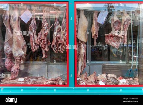 Fresh Hanging Meat Carcass On A Stylish Butcher Shop Window And Its Fridged Counter With Meat