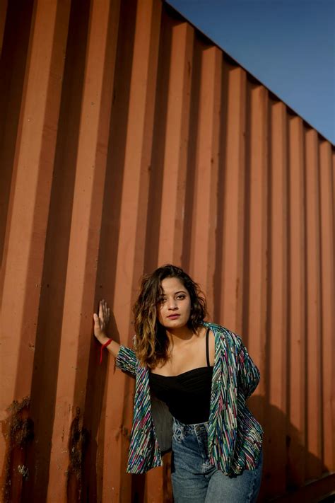 A Young Woman Stands Against A Large Rust Colored Metal Container She