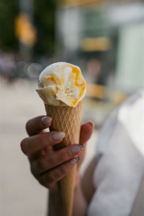 바닐라 아이스크림 콘을 쥔 손의 클로즈업 · 무료 스톡 사진