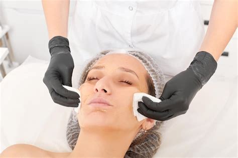 Premium Photo Cosmetologist Removing Facial Cream Mask From Woman Face Skin With Cosmetic
