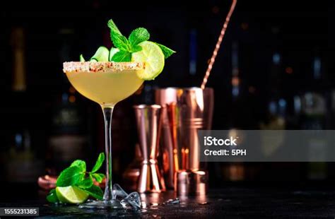 데킬라 라임 주스 시럽 민트 얼음을 곁들인 오이 마가리타 알코올 칵테일 음료는 소금에 절인 칠리 페퍼 테두리 어두운 배경 바 도구 및 병으로 장식되어 있습니다 0명에 대한