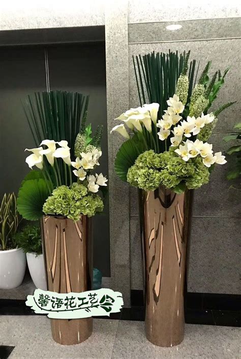 Dos Jarrones Con Flores Y Vegetación En Un Mostrador Junto A Un Espejo