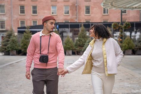 Trendy Young Hispanic Couple Holding Hands And Strolling Along Square