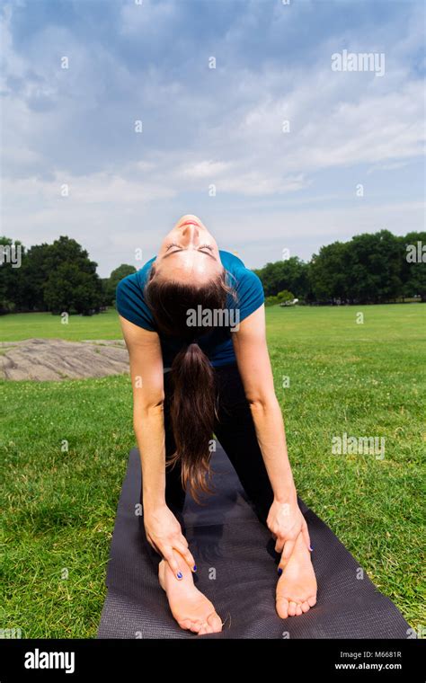 Young Caucasian Woman Practices Yoga In Central Park Nyc While Wearing