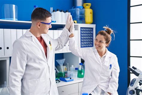 Man And Woman Scientists High Five With Hands Raised Up At Laboratory