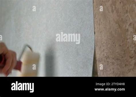 Close Up Sheet Of Blue Papper Wallpaper Is Glued To The Wall With A Special Construction Roller