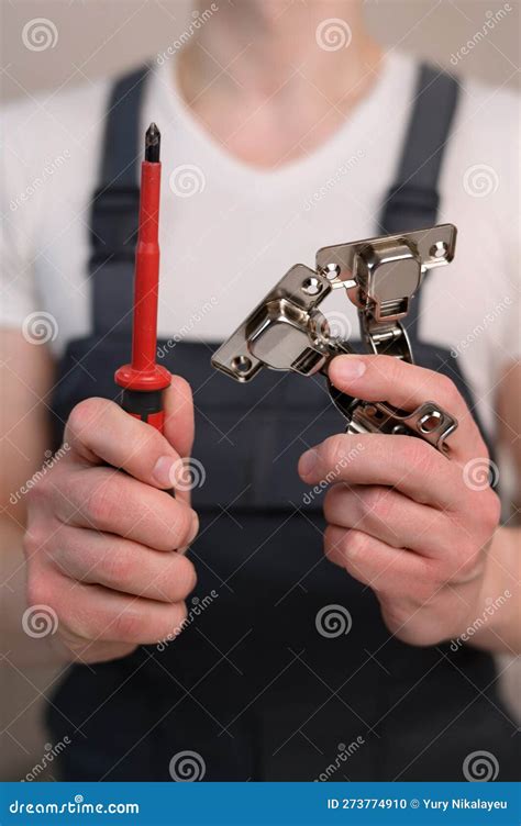 Furniture Assembler Holds A Furniture Hinge And A Screwdriver In His