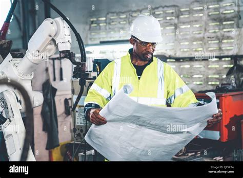 african american factory worker working with adept robotic arm in a